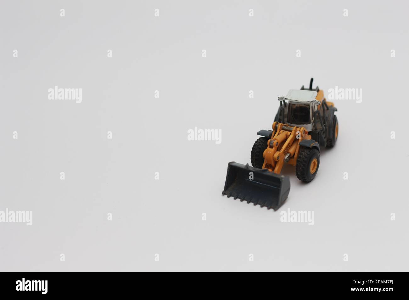 a close up of miniature orange wheel loader toy isolated on white ...