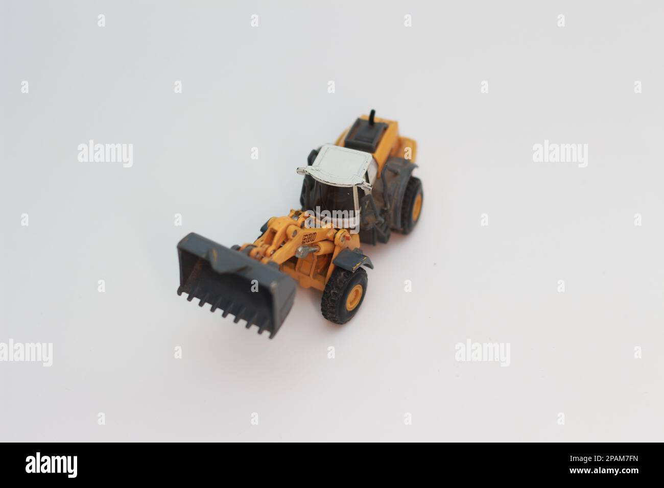 a close up of miniature orange wheel loader toy isolated on white ...