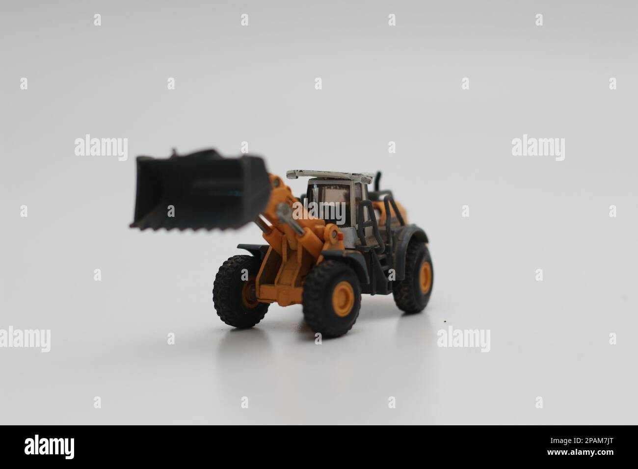 a close up of miniature orange wheel loader toy isolated on white ...