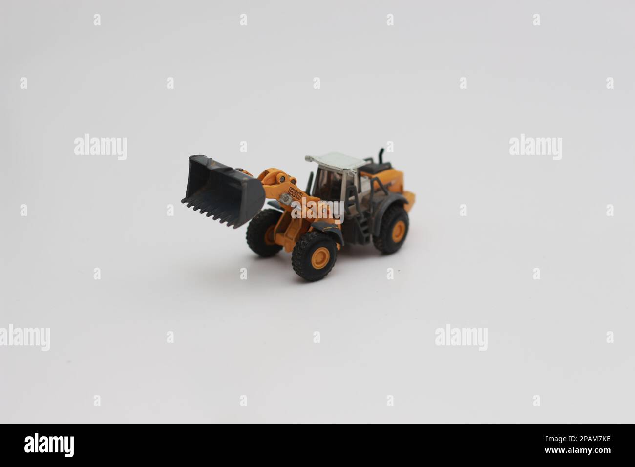 a close up of miniature orange wheel loader toy isolated on white ...