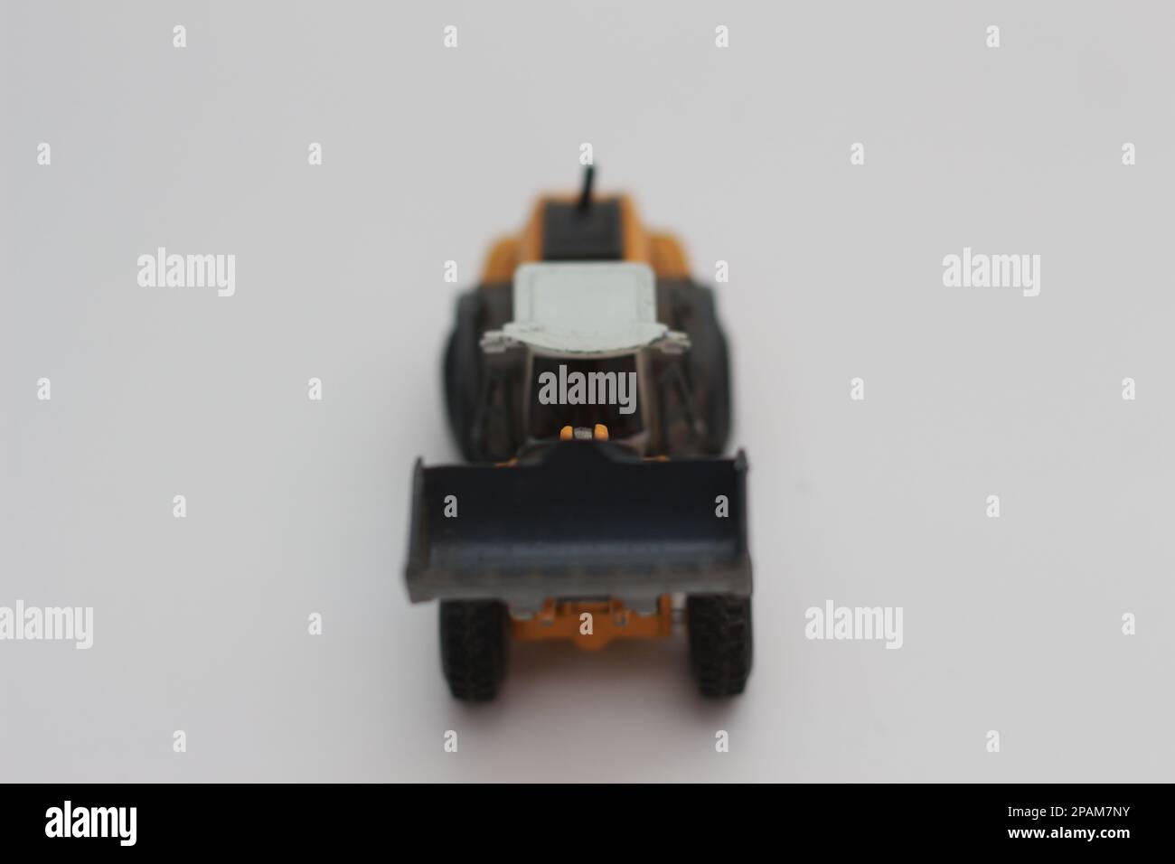 a close up of miniature orange wheel loader toy isolated on white ...