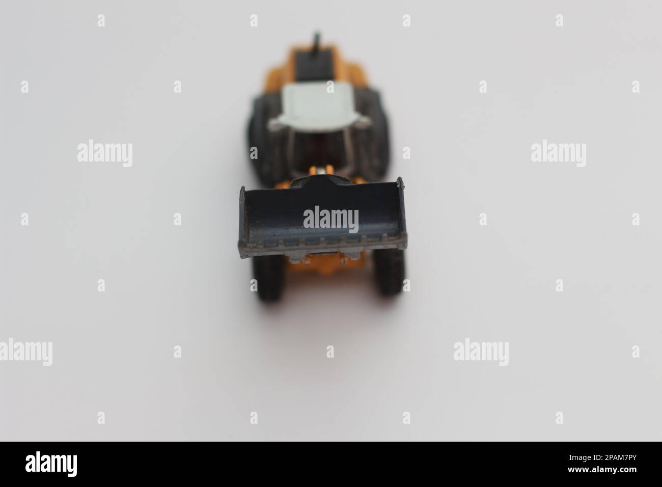a close up of miniature orange wheel loader toy isolated on white ...