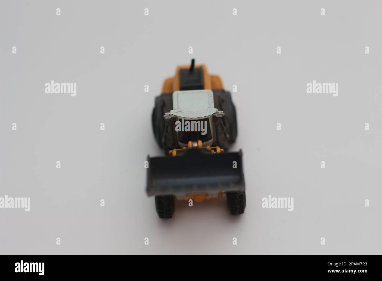 a close up of miniature orange wheel loader toy isolated on white ...