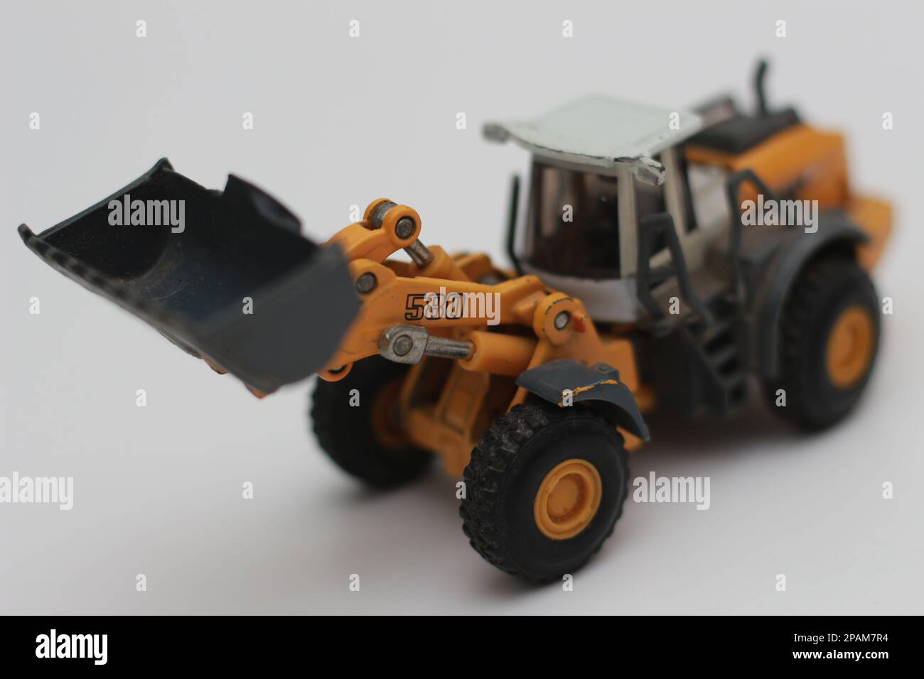 a close up of miniature orange wheel loader toy isolated on white ...