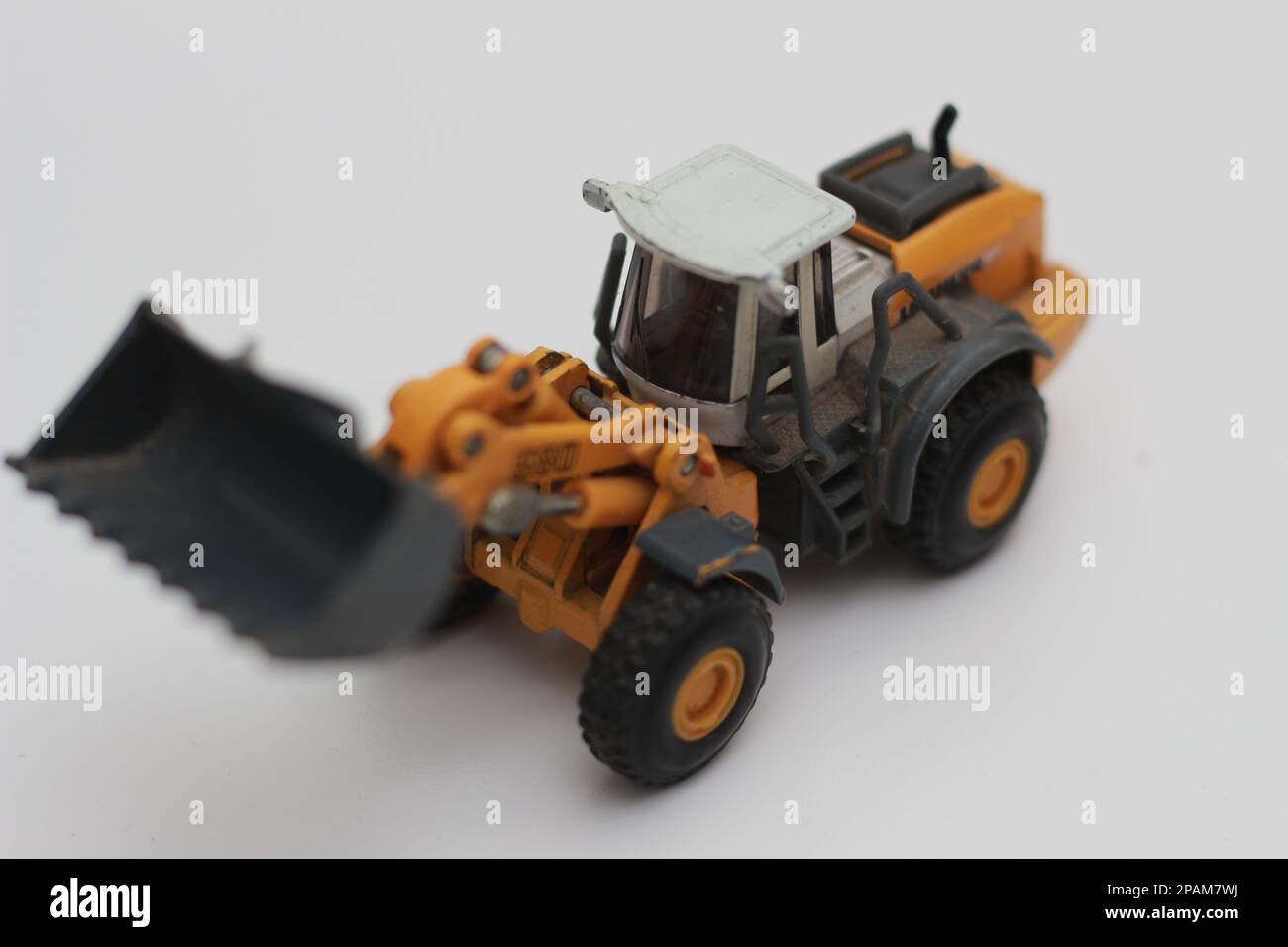a close up of miniature orange wheel loader toy isolated on white ...