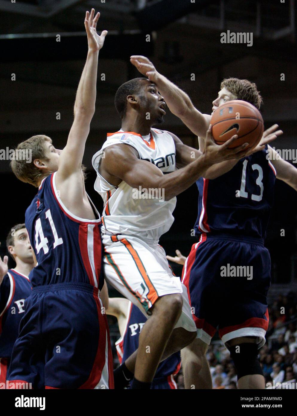 Miami forward Raymond Hicks, center, goes up for a shot as Penn's ...