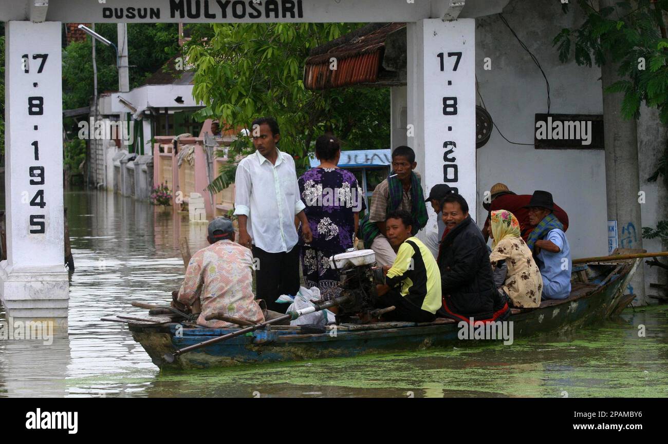 Indonesian residents use a boat to cross a flooded area in Gresik, East Java, Indonesia ...