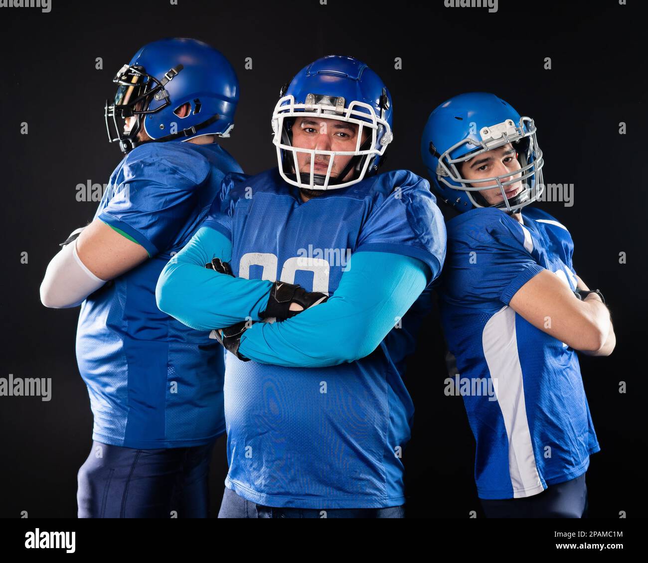 Portrait of three men in blue American football uniforms standing with ...