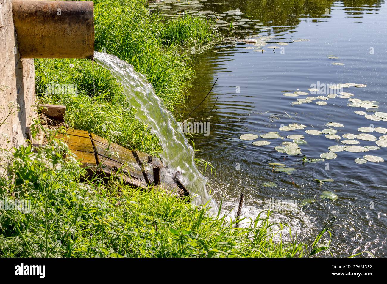 Drain water from the pipe into the river Stock Photo - Alamy