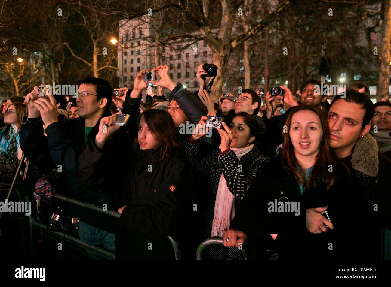 People watch and take pictures as fireworks explode over the London Eye ...