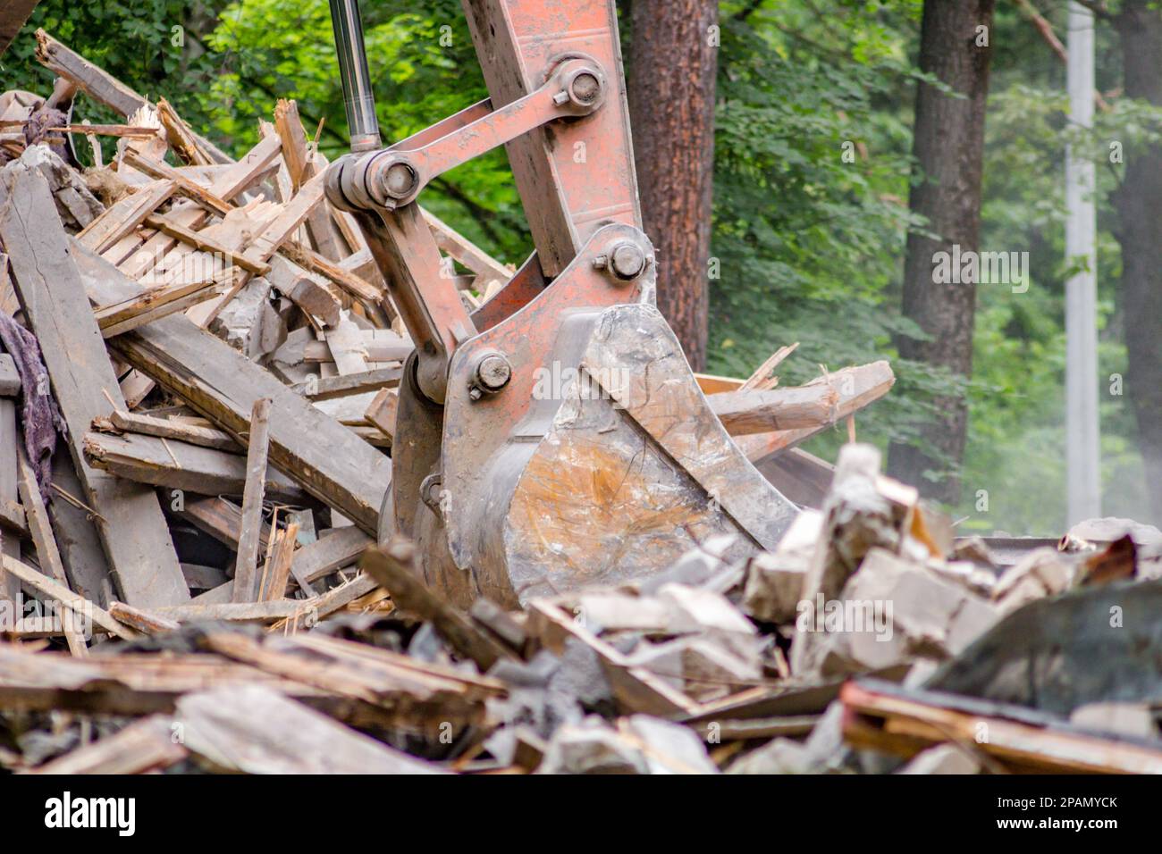 Excavator bucket loads construction debris after the demolition of the ...