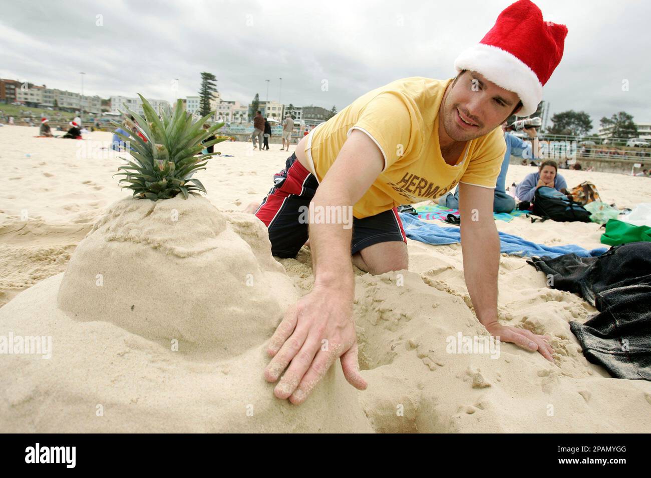 English tourist Alex Rutter builds a sandcastle with a pineapple for a ...