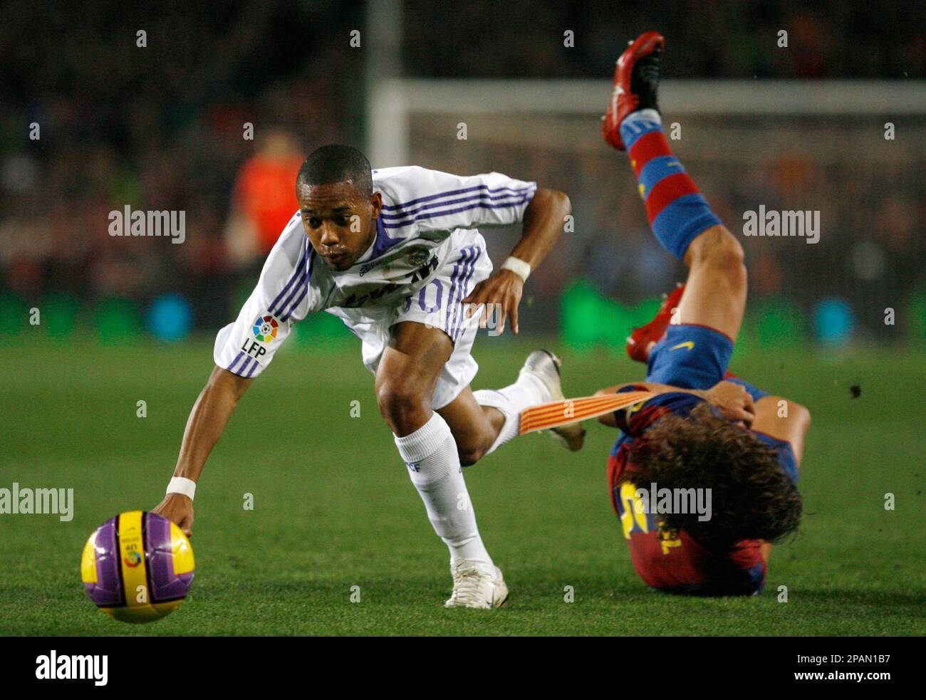 Real Madrid's Robinho, from Brazil, eyes the ball after a tackle by FC ...