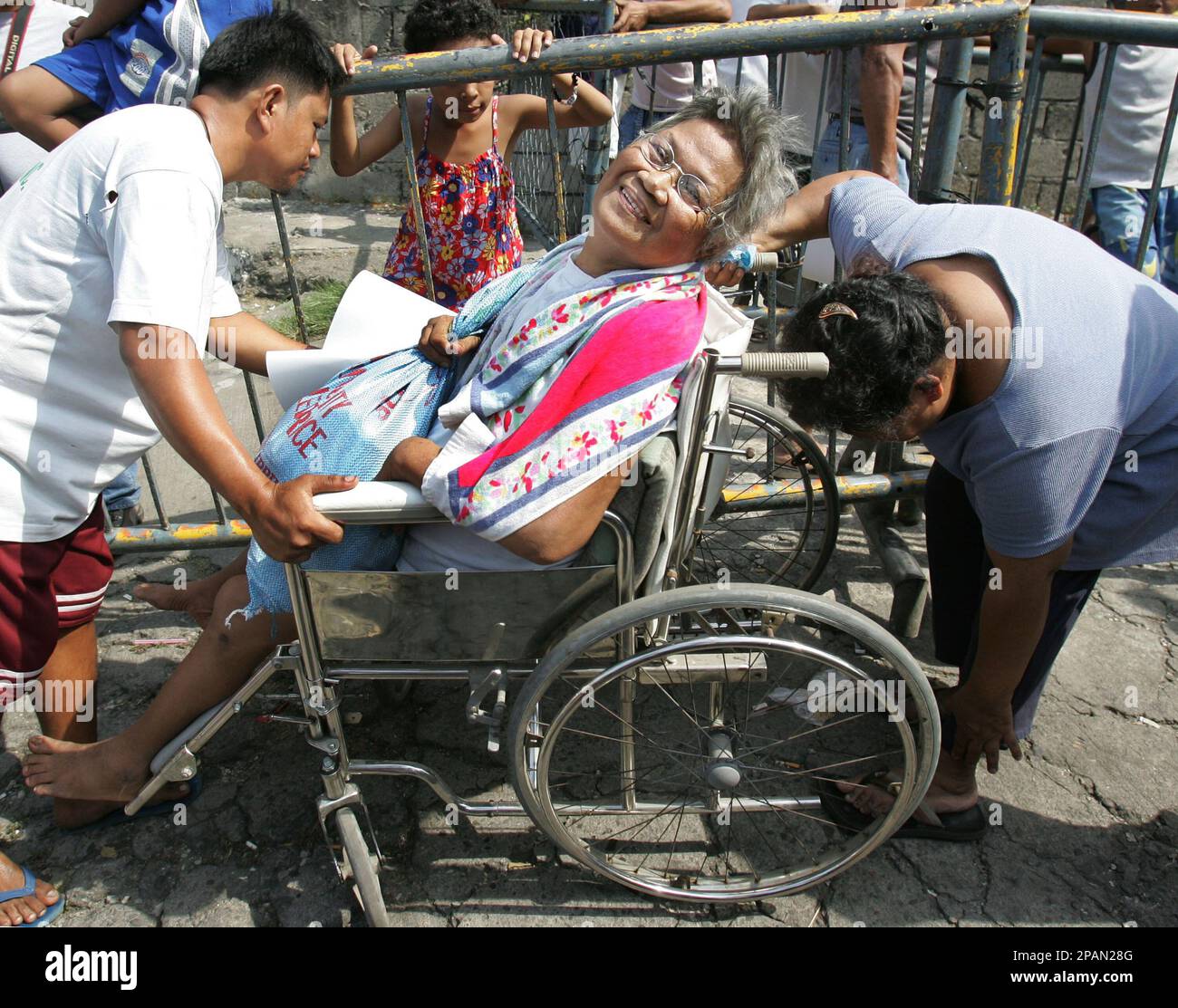 A disabled elderly Filipino woman smiles as she holds a bag of food ...