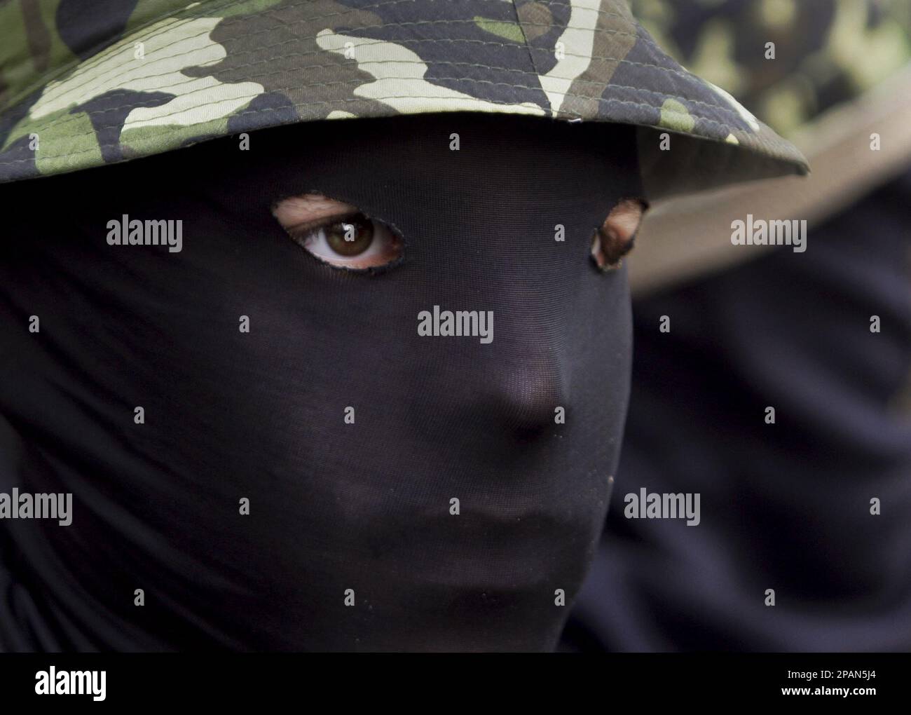 A Palestinian Hamas supporter wears a mask during the funeral of a ...