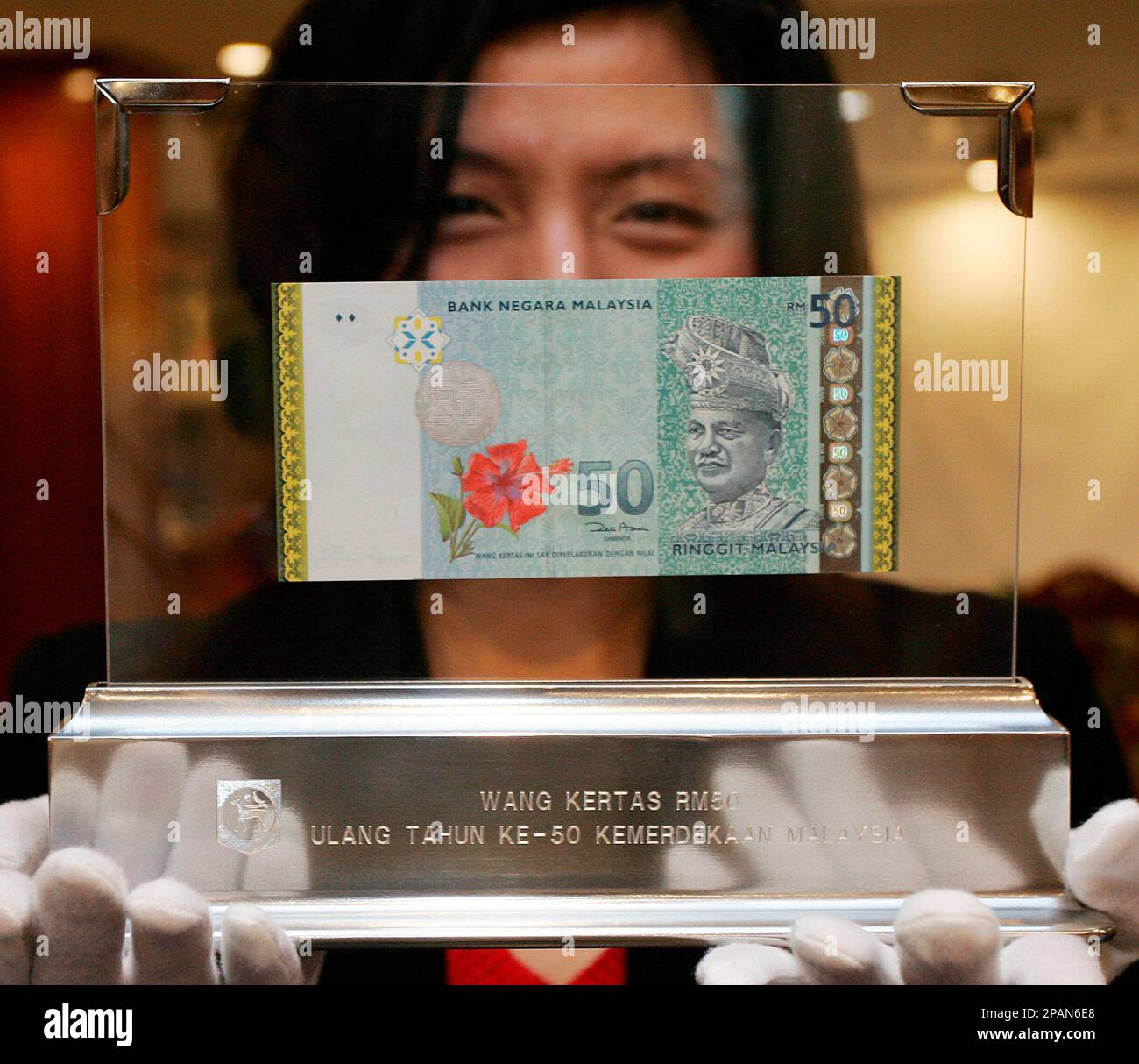 An employee of the Malaysia National Bank displays a new Malaysia RM 50 ...