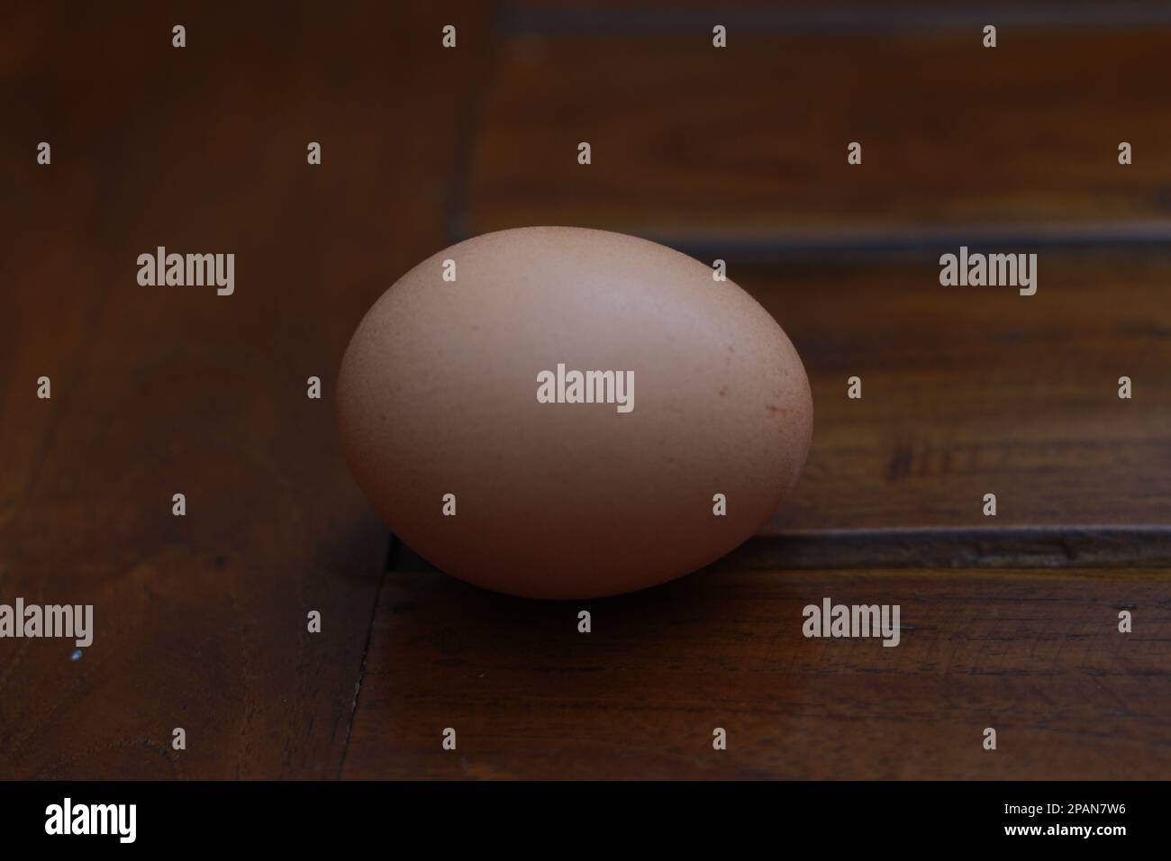 a close up of a chicken egg isolated on a natural patterned wooden ...