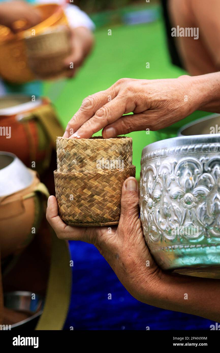close up of hands of asian woman giving alms during buddhist ceremony ...