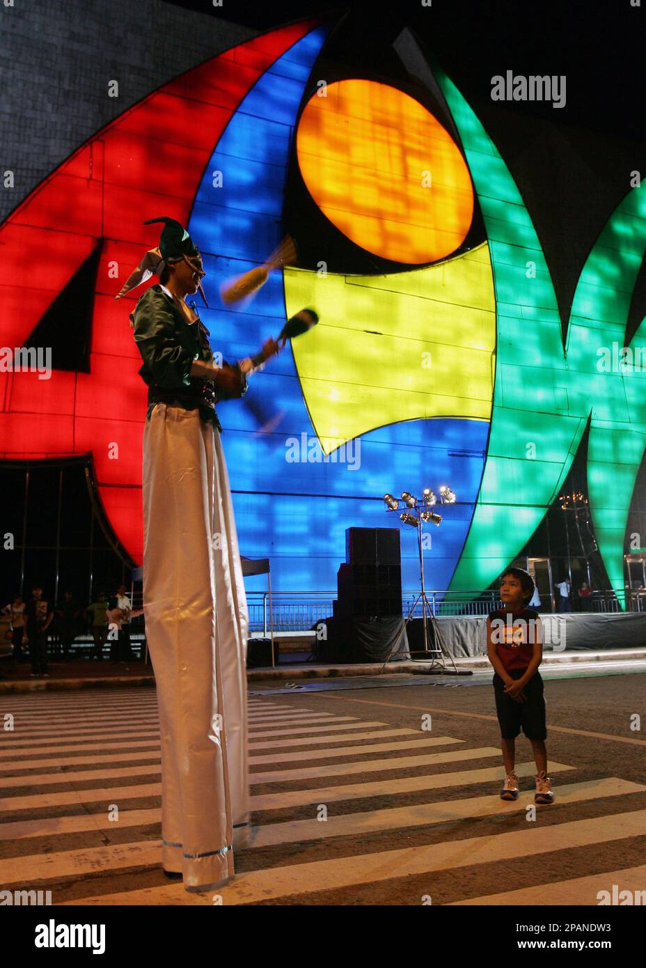 A circus juggler, walking on stilts, performs in front of a boy during ...