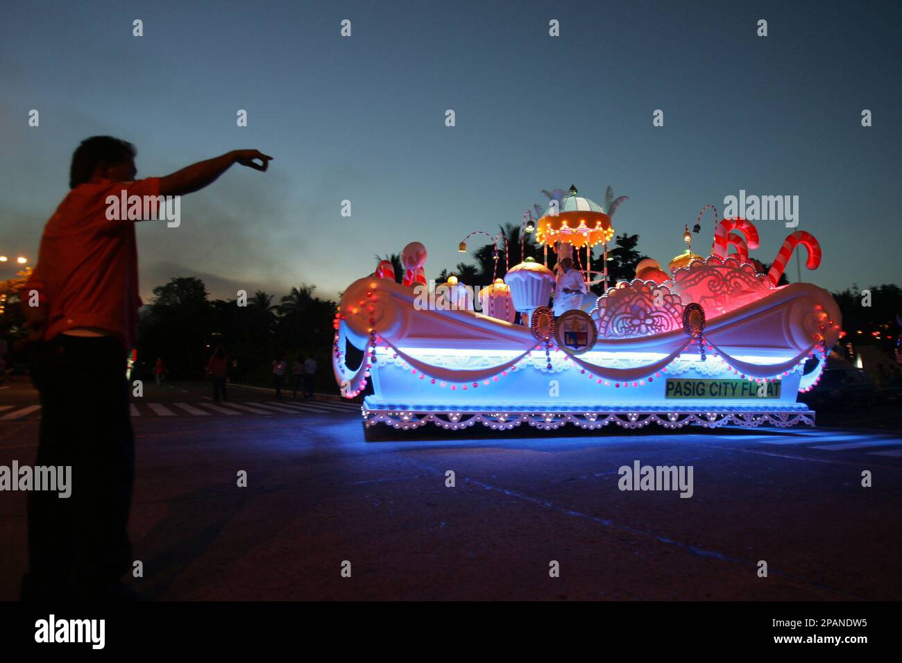 A volunteer directs traffic as a float depicting a Filipino tradition ...