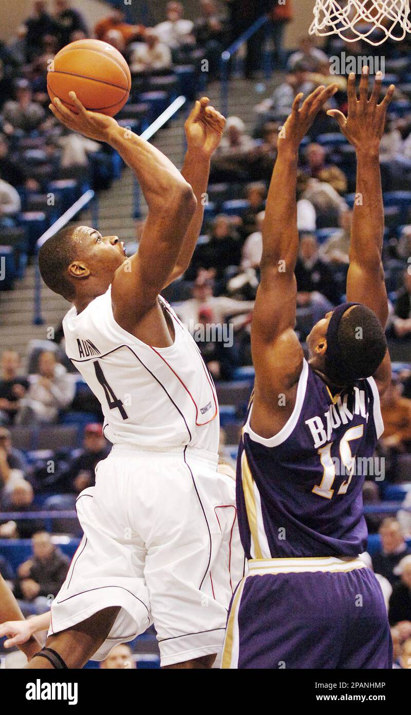 Connecticut's Jeff Adrien scores two points while being guarded by ...