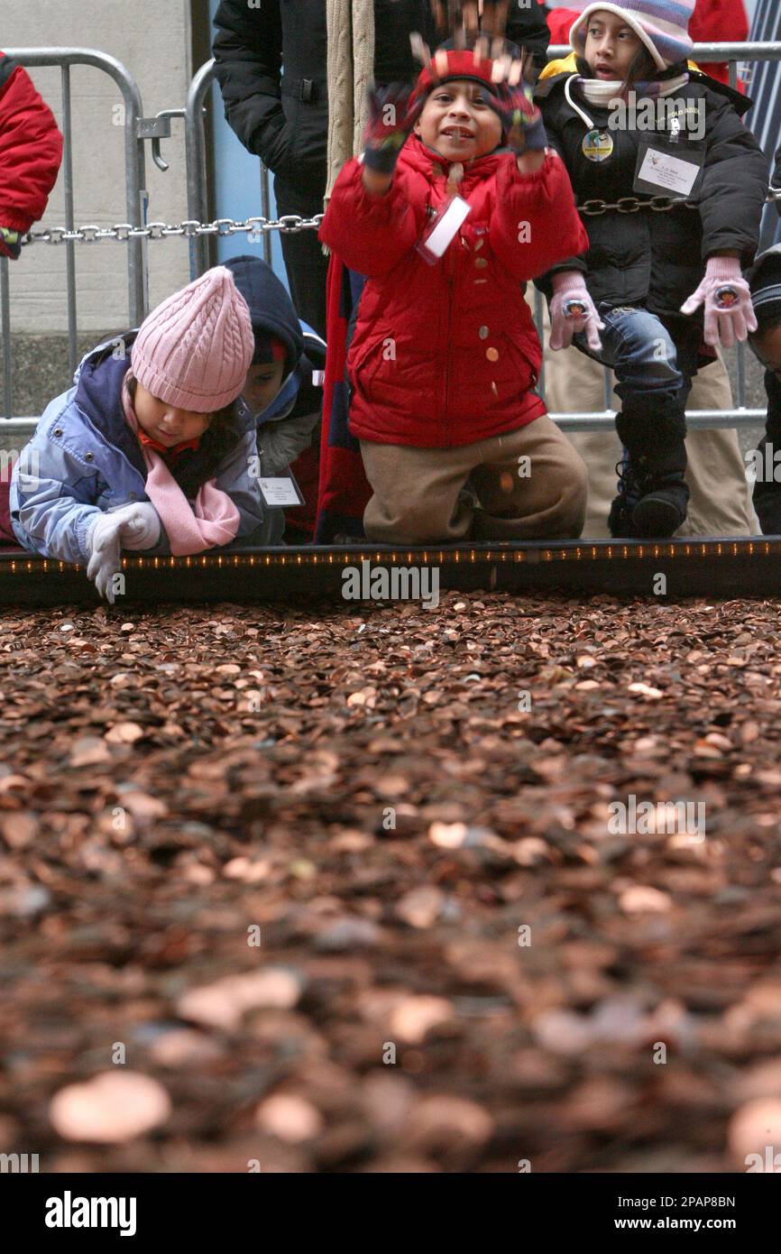 Children who helped collect pennies play with them during a ceremony to ...
