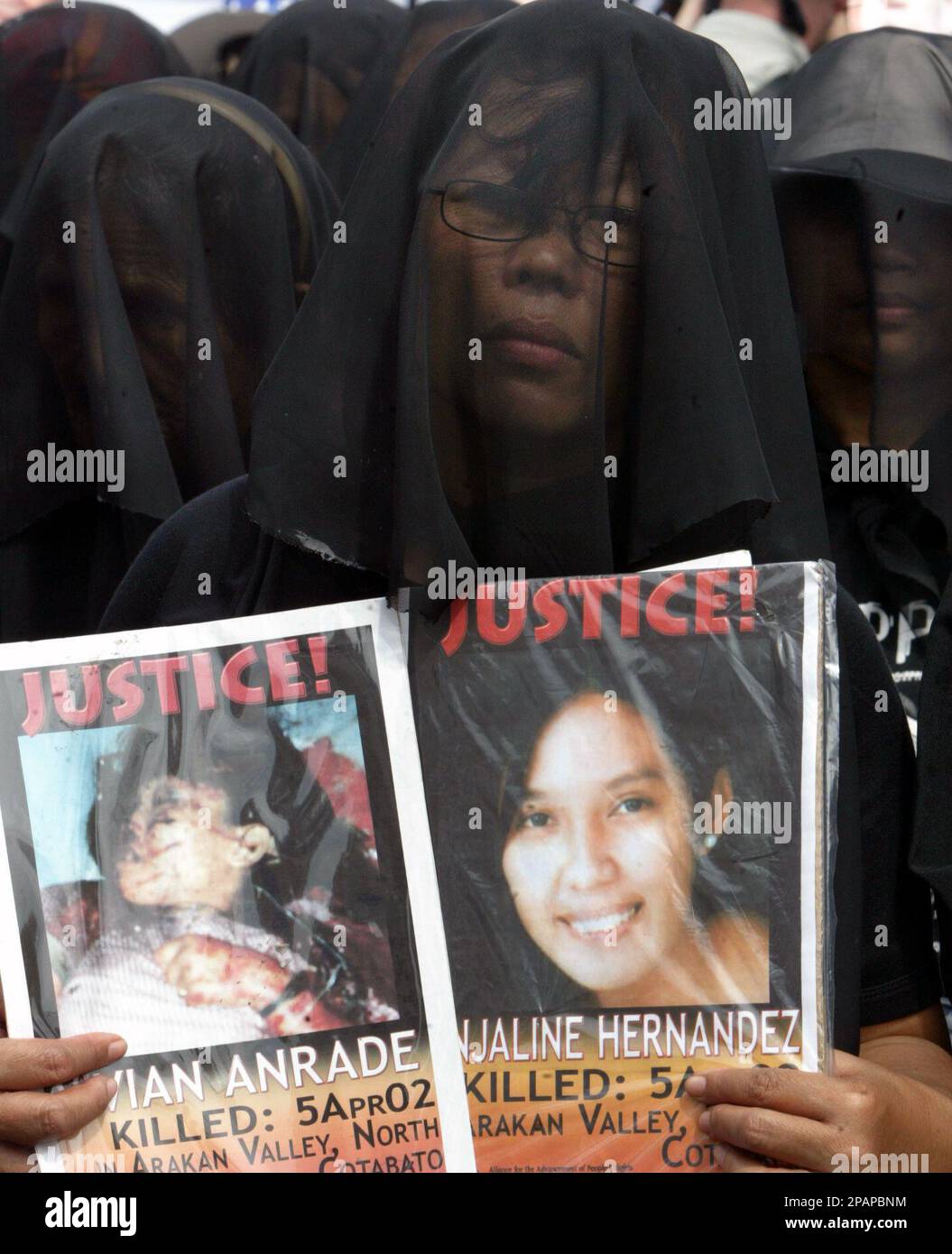 Veiled Evangeline Hernandez holds a poster of her slain daughter ...