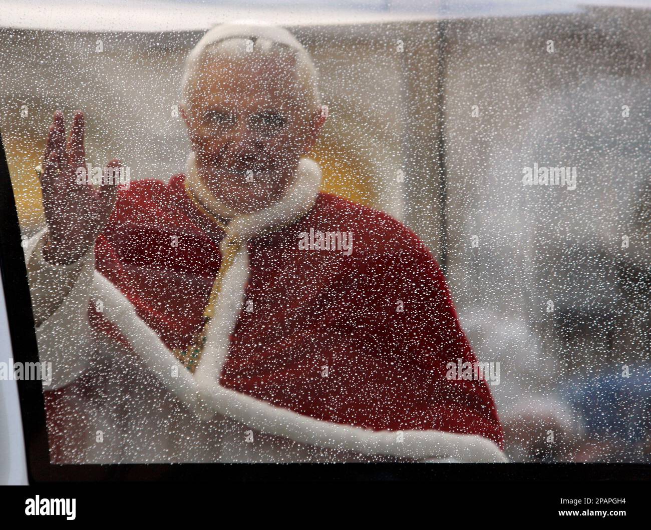 Pope Benedict XVI waves from behind his popemobile window covered in ...