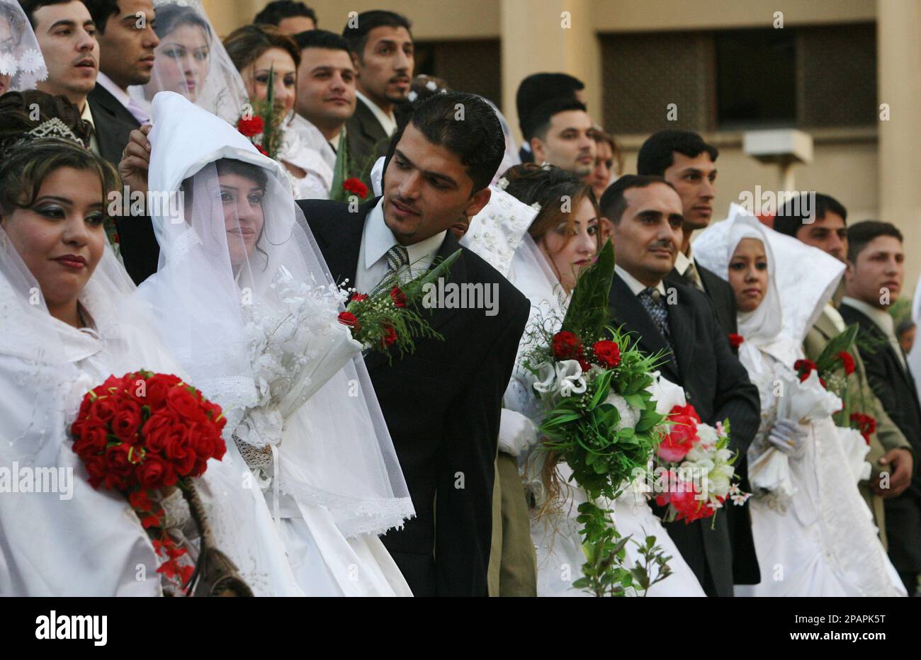 An Iraqi husband adjusts a dress on his newly married wife while posing ...