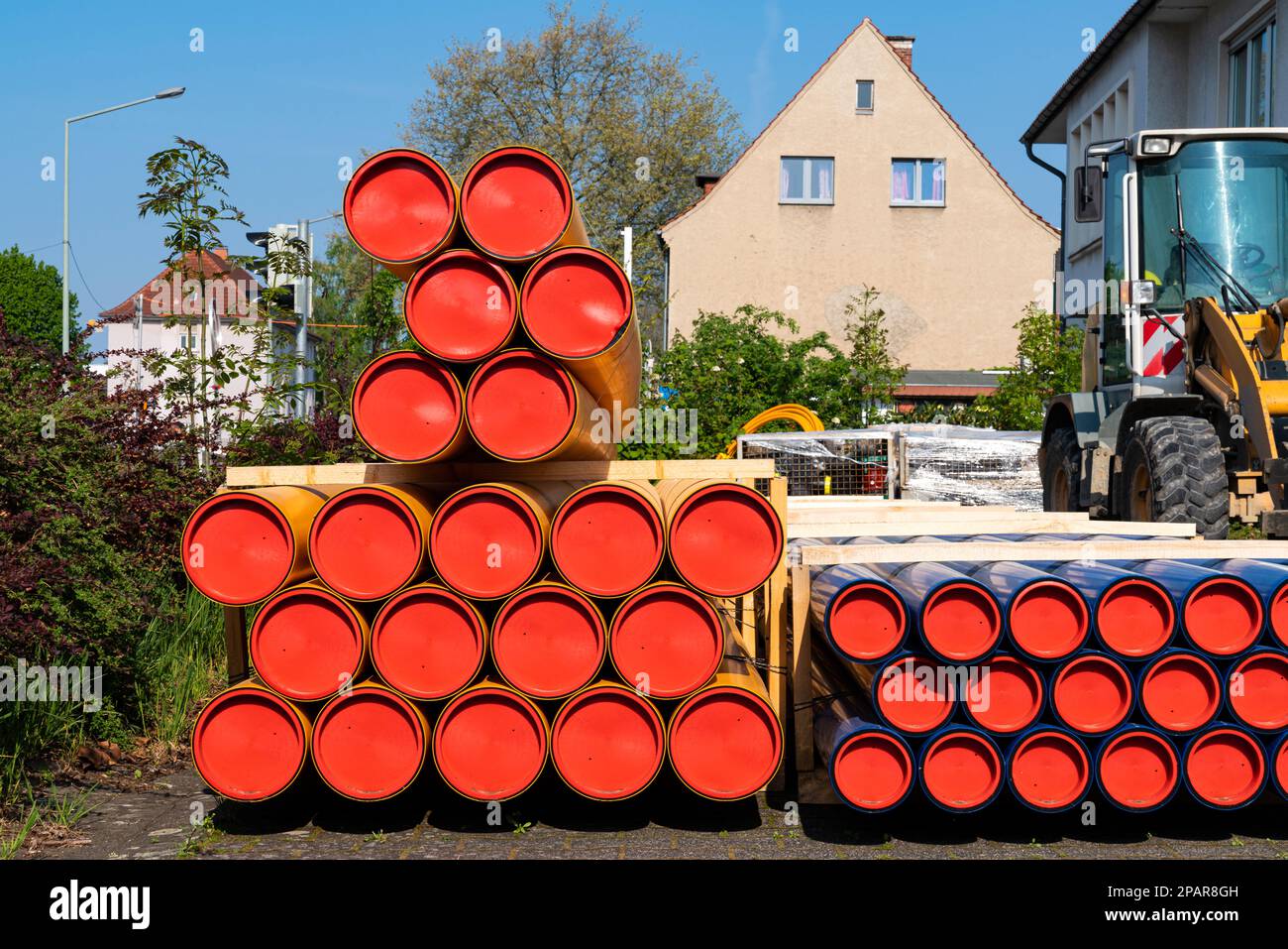 Construction site in city. Stack of orange-yellow and blue PVC conduit ...