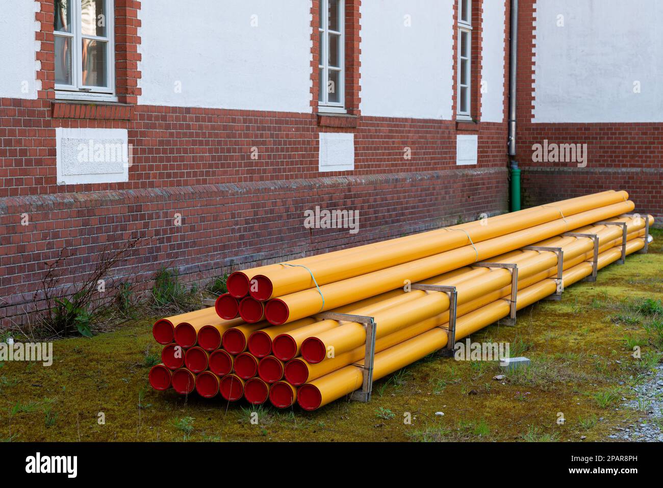 Construction site in city. Stack of orange-yellow PVC conduit pipes ...
