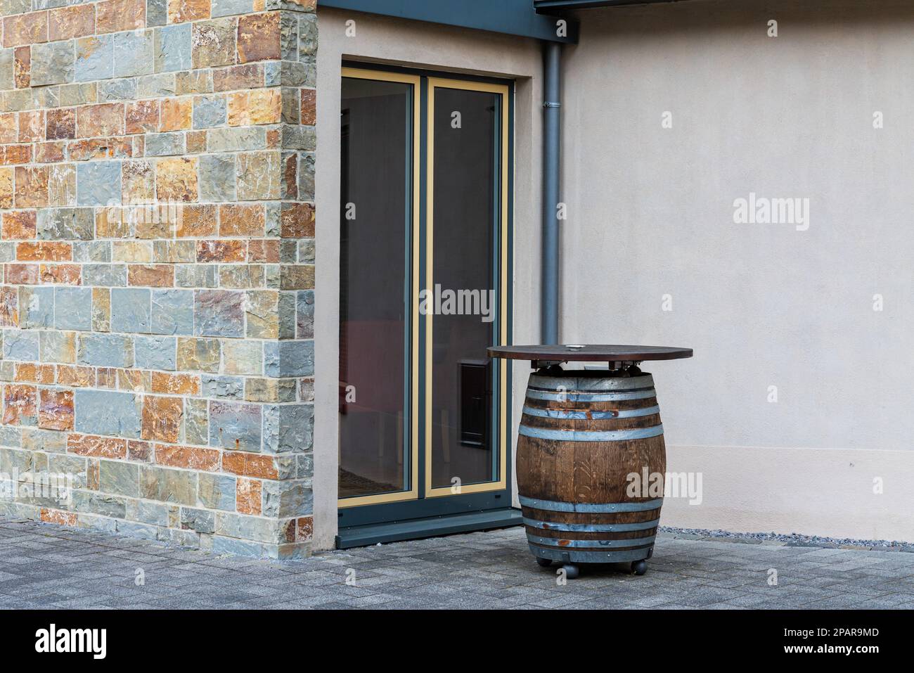 Bar table in the form of a wooden barrel in front of a glass door ...