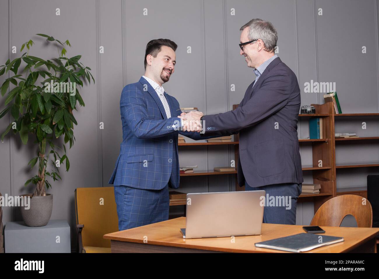 Two businessman in blue suits are happy and joyful because of ...