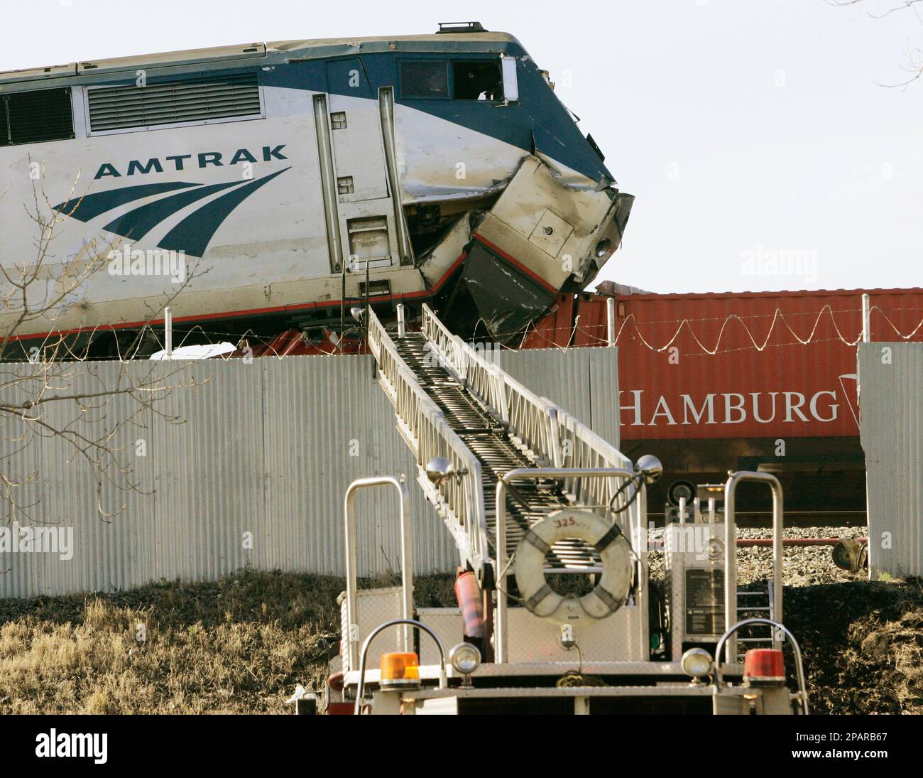 A fire truck ladder extends toward the scene where an Amtrak passenger ...
