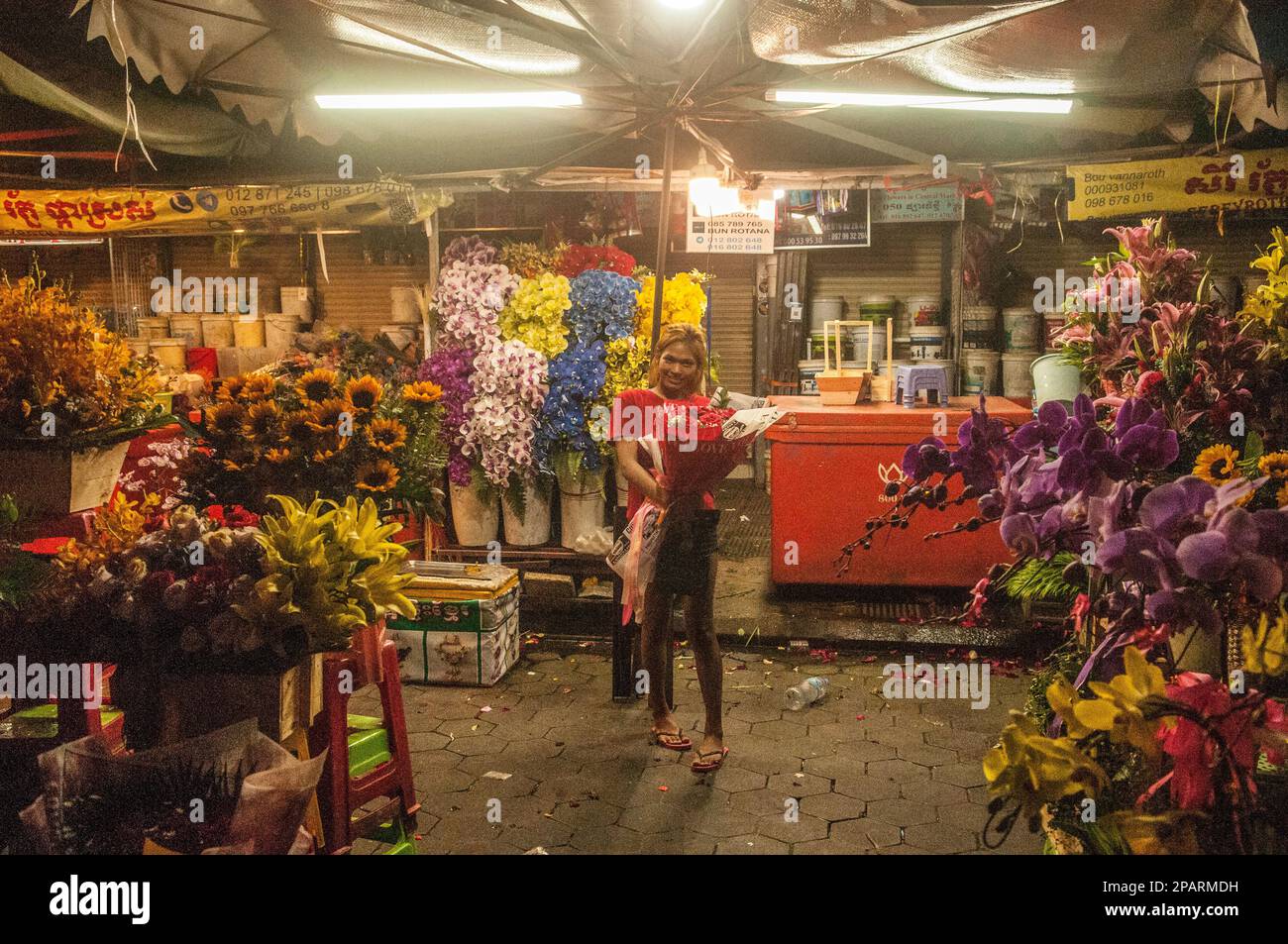 A beautiful Cambodian woman w/ a bouquet of roses at a street stall ...