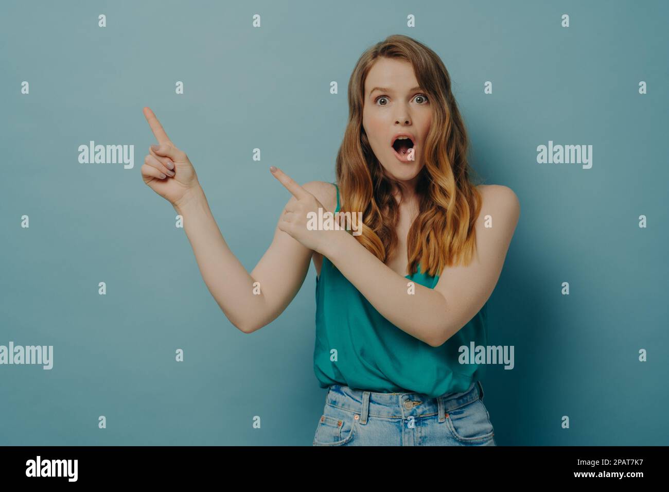 Surprised young female in casual wear pointing to right side with index ...