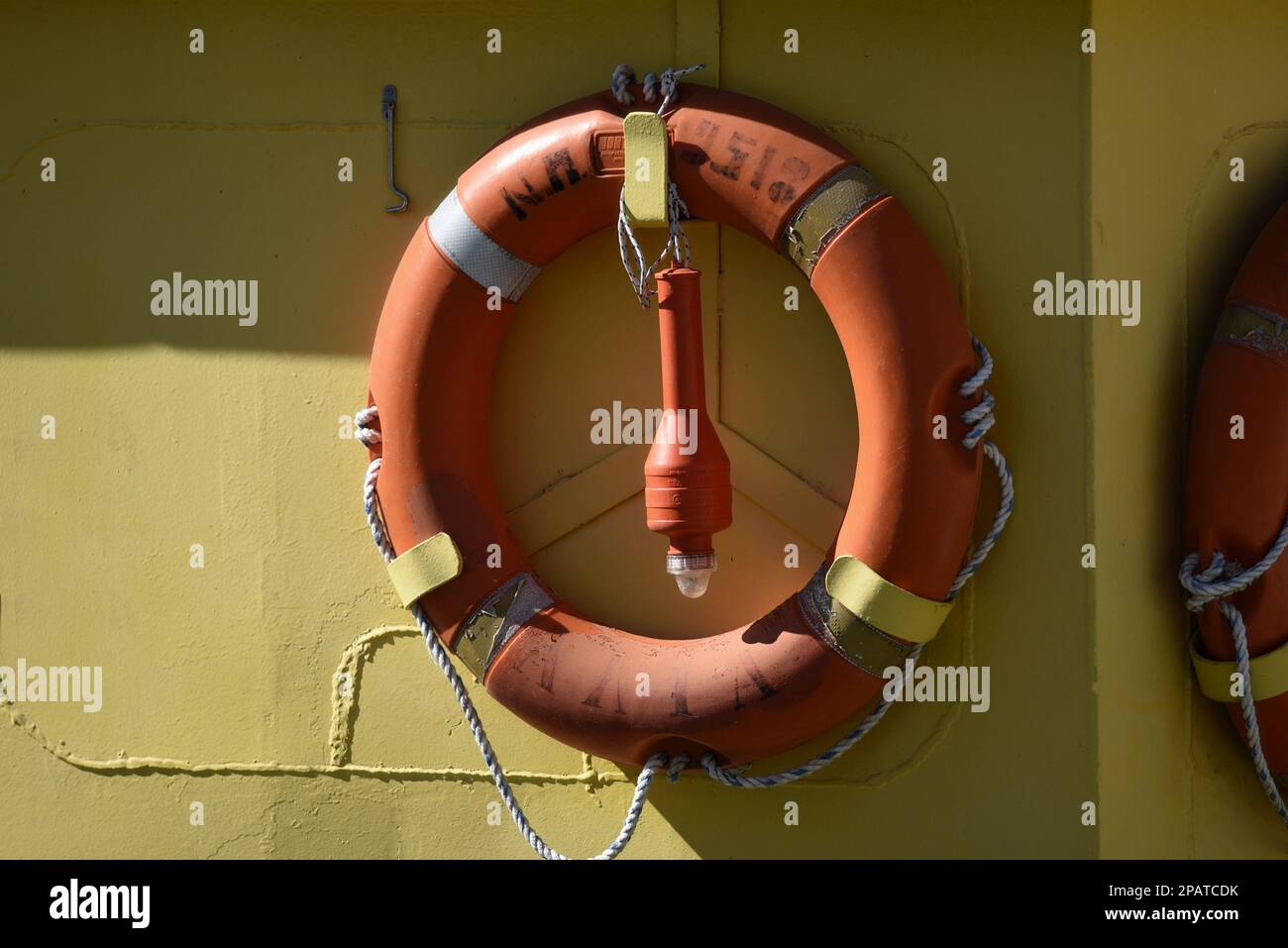 Orange life buoy ring with a floating emergency light on a yellow ...