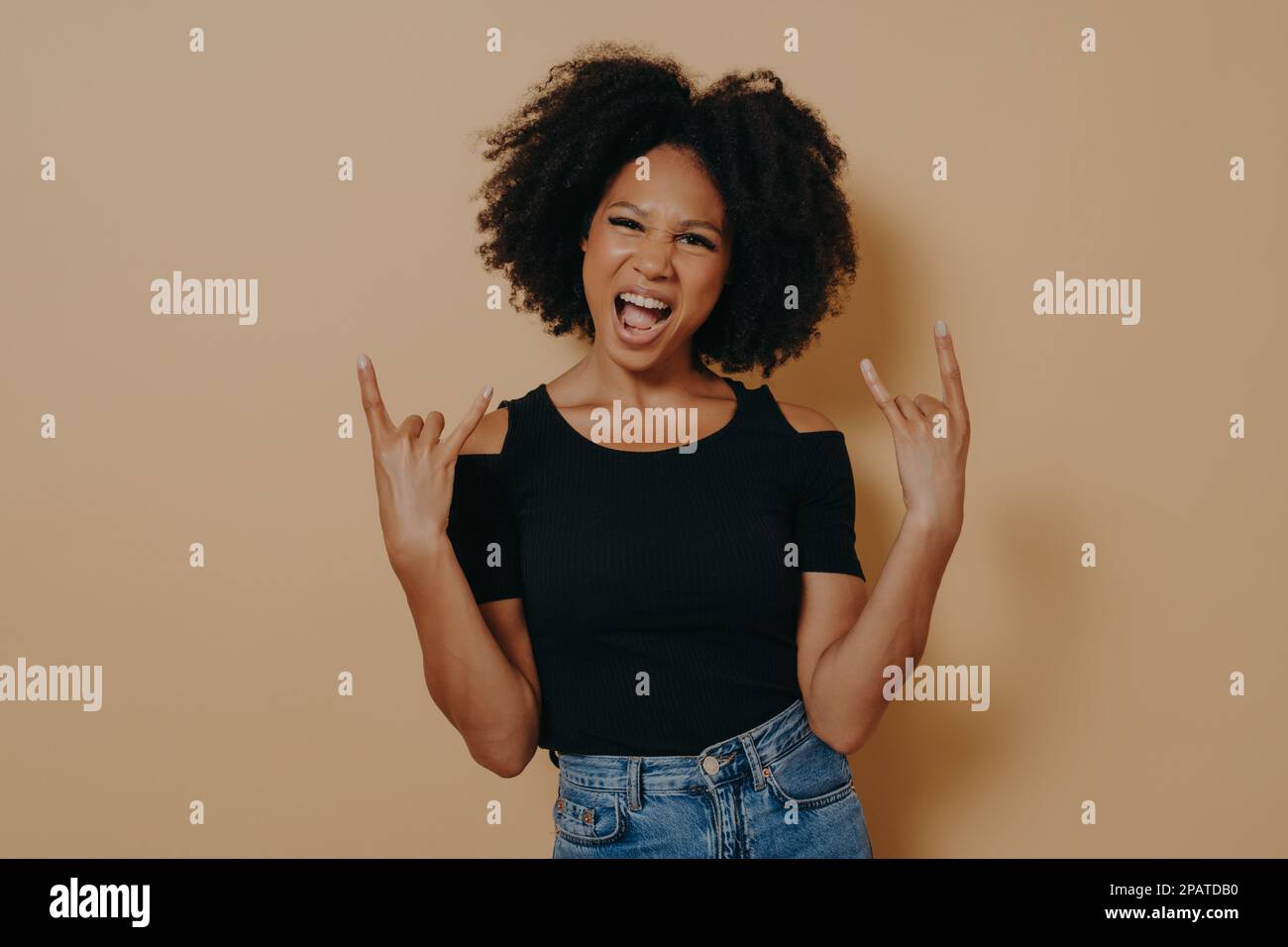 Rock star. Young self confident afro american woman holding both hands ...