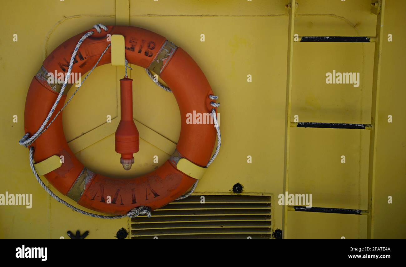Orange life buoy ring with a floating emergency light on a yellow ...