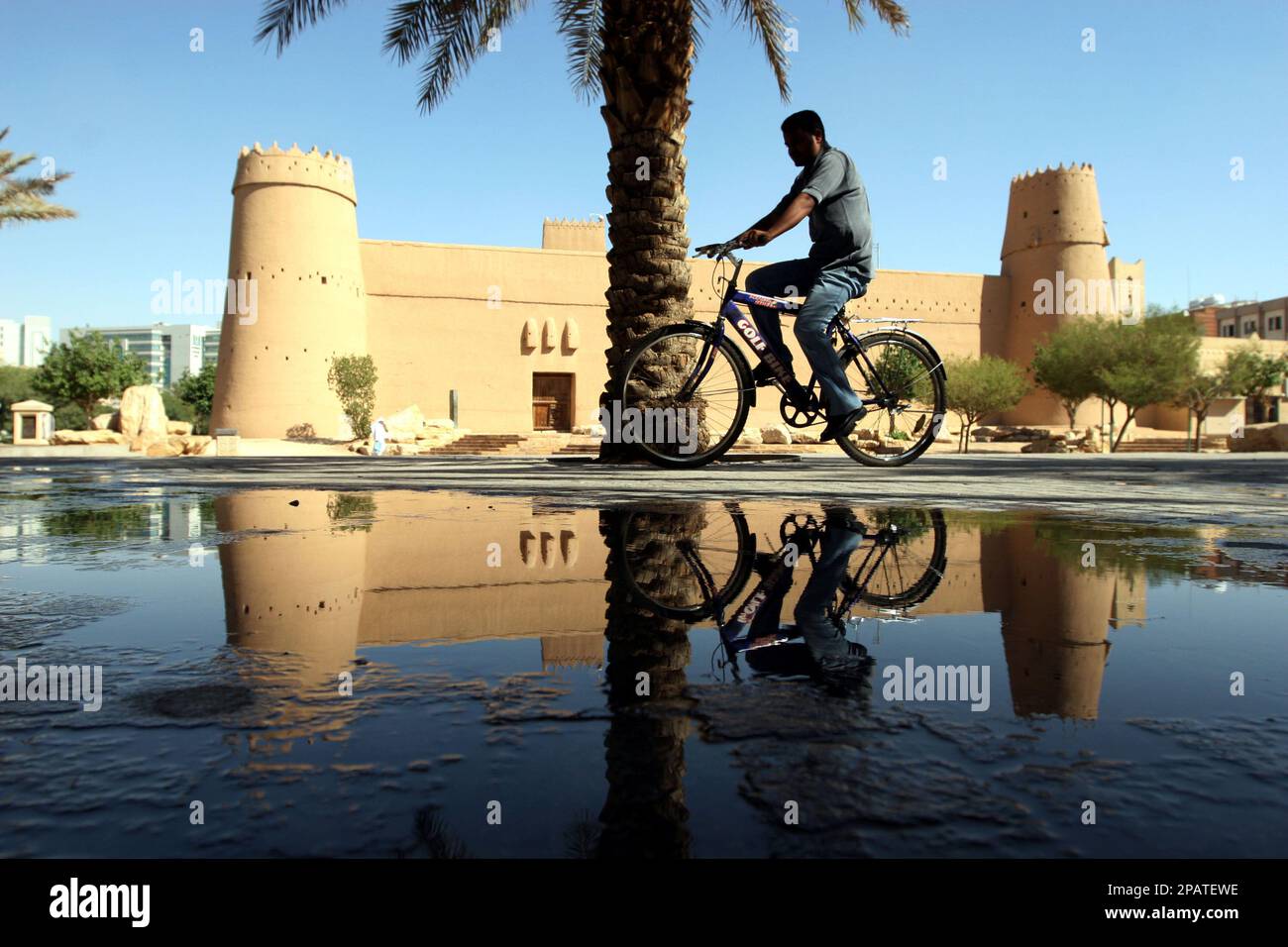 A Saudi man rides his bike as seen the Masmak Fortress (Qasre al-Masmak ...