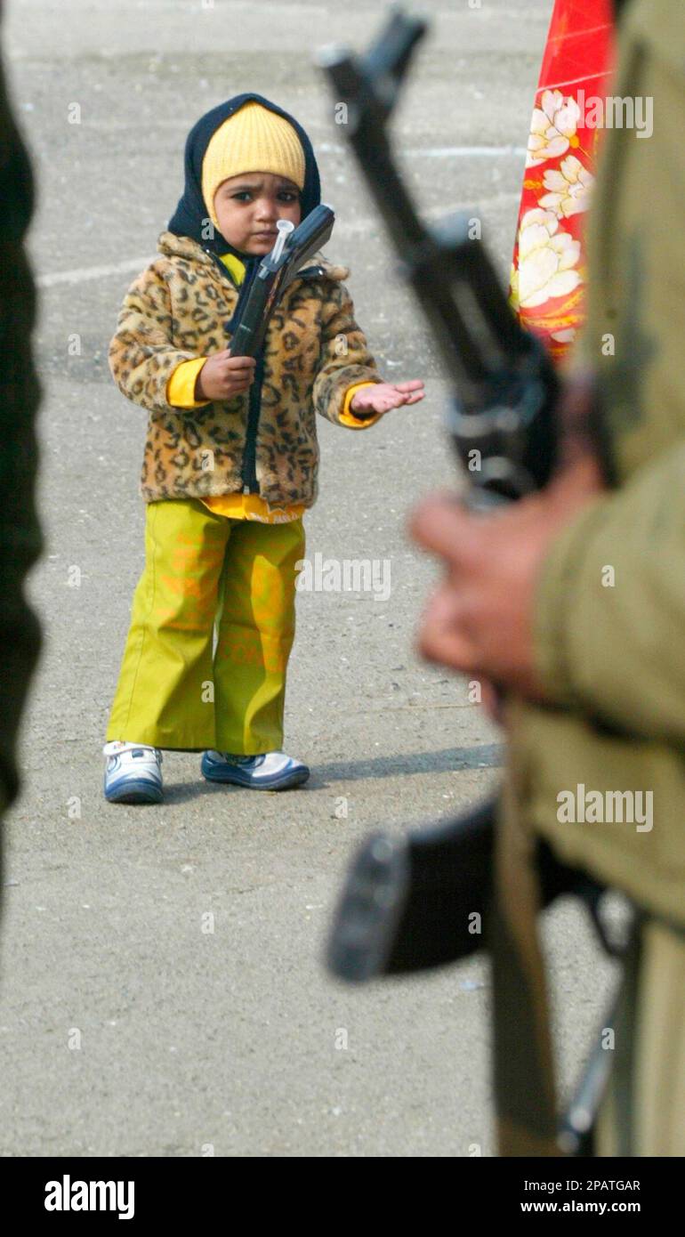 An Indian paramilitary soldier, right, stands guard as a tourist child ...