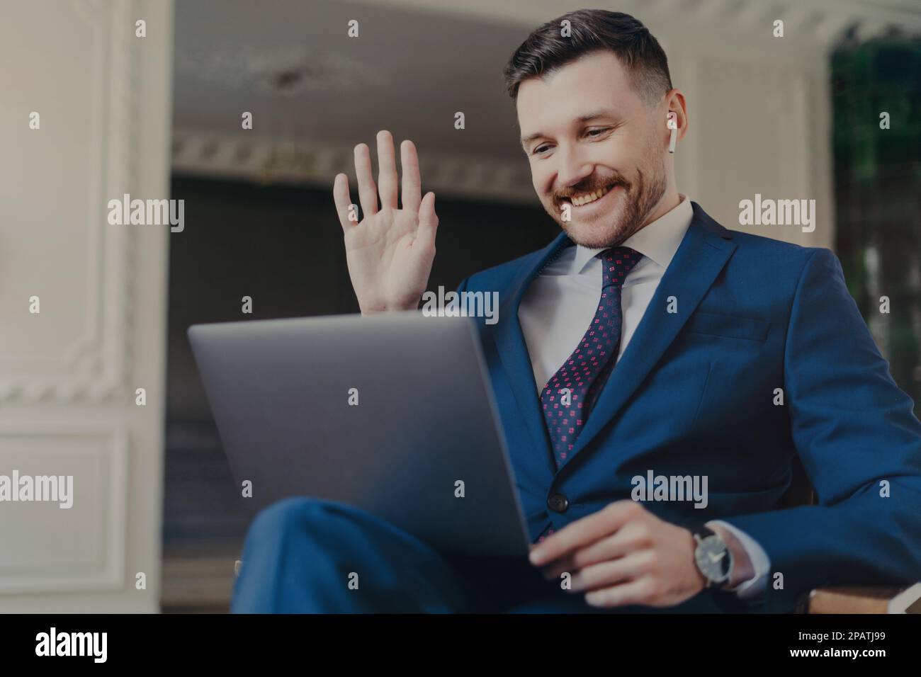 Positive male corporate worker makes video call via laptop computer and ...