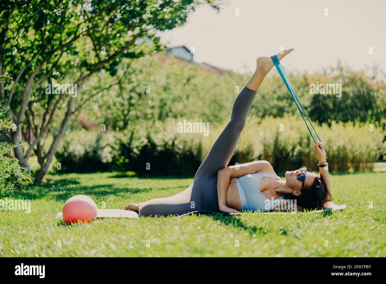 Horizontal shot of flexible woman raises leg does exercises with ...