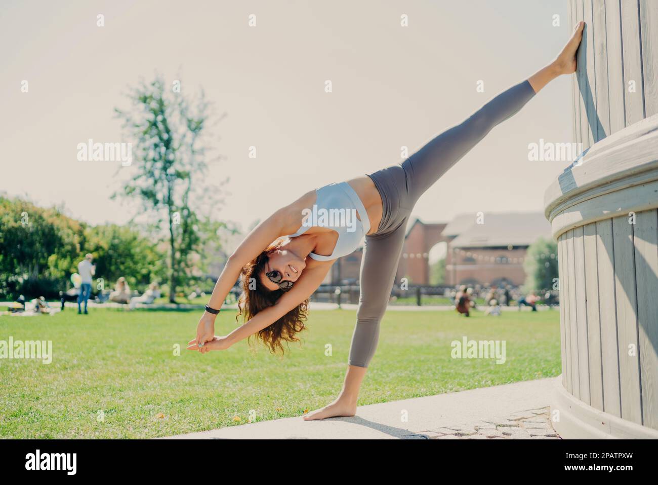 Flexible slim woman does stretching exercises outdoor stays in good ...