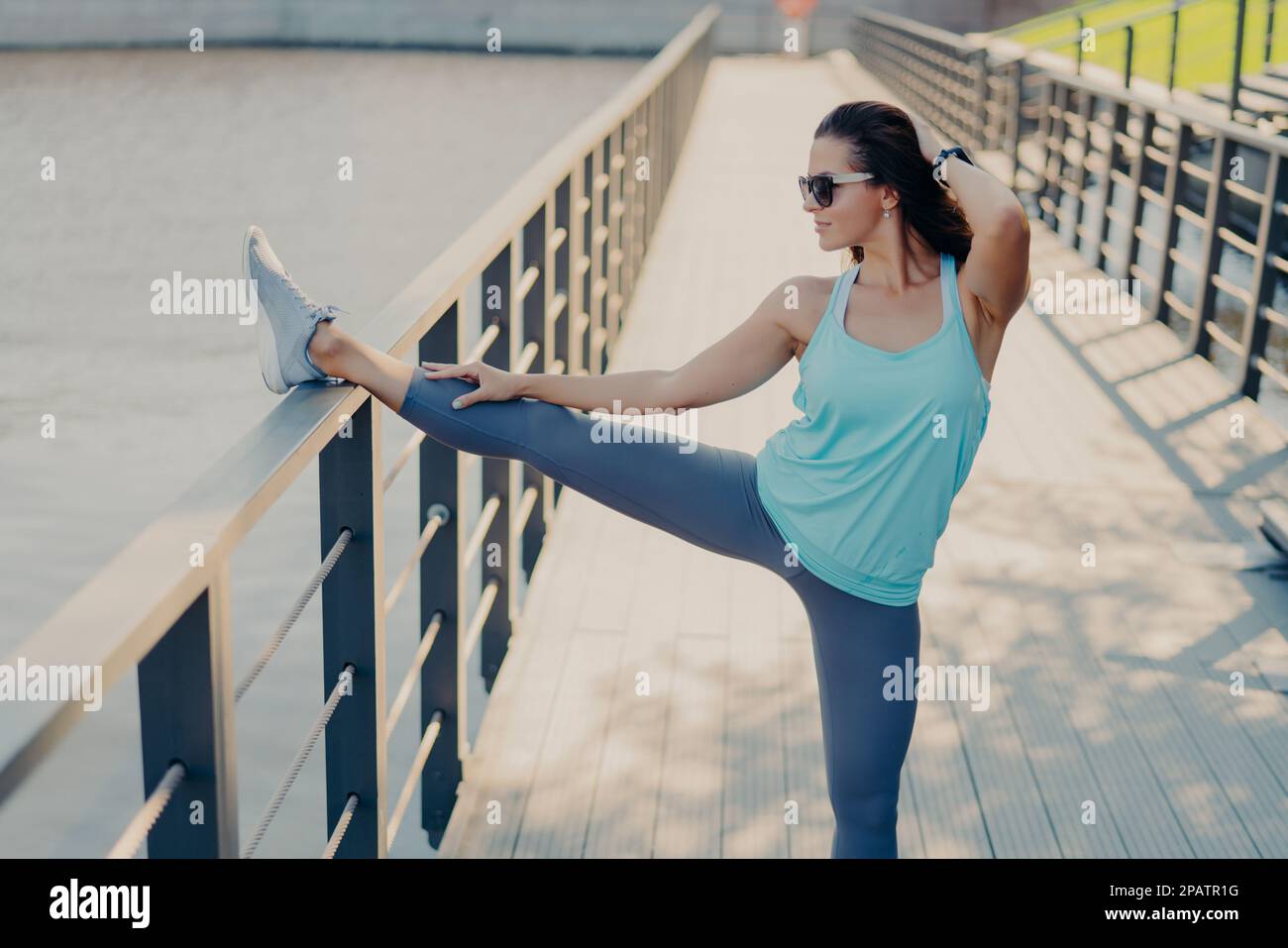 Full length shot of active woman stretches legs before run leans at ...