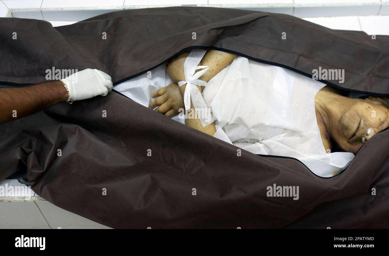 ** EDS NOTE GRAPHIC CONTENT ** A worker unzips a body bag where a ...