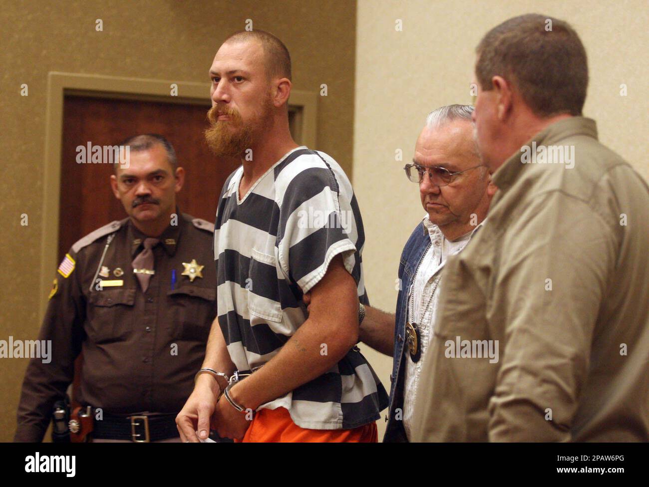 Chris Collings, second from left, is flanked by sheriff's deputies as ...