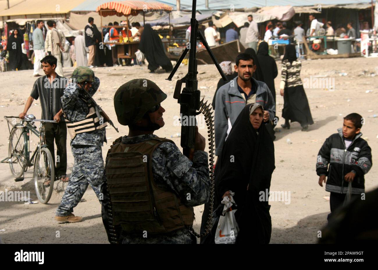 An Iraqi policeman holds up his weapon while patrolling the streets of ...