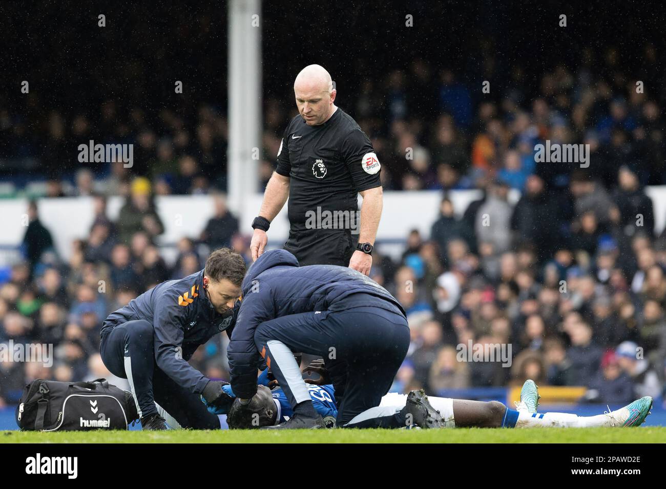 Referee Simon Hooper checks on an injured Amadou Onana #8 of Everton ...