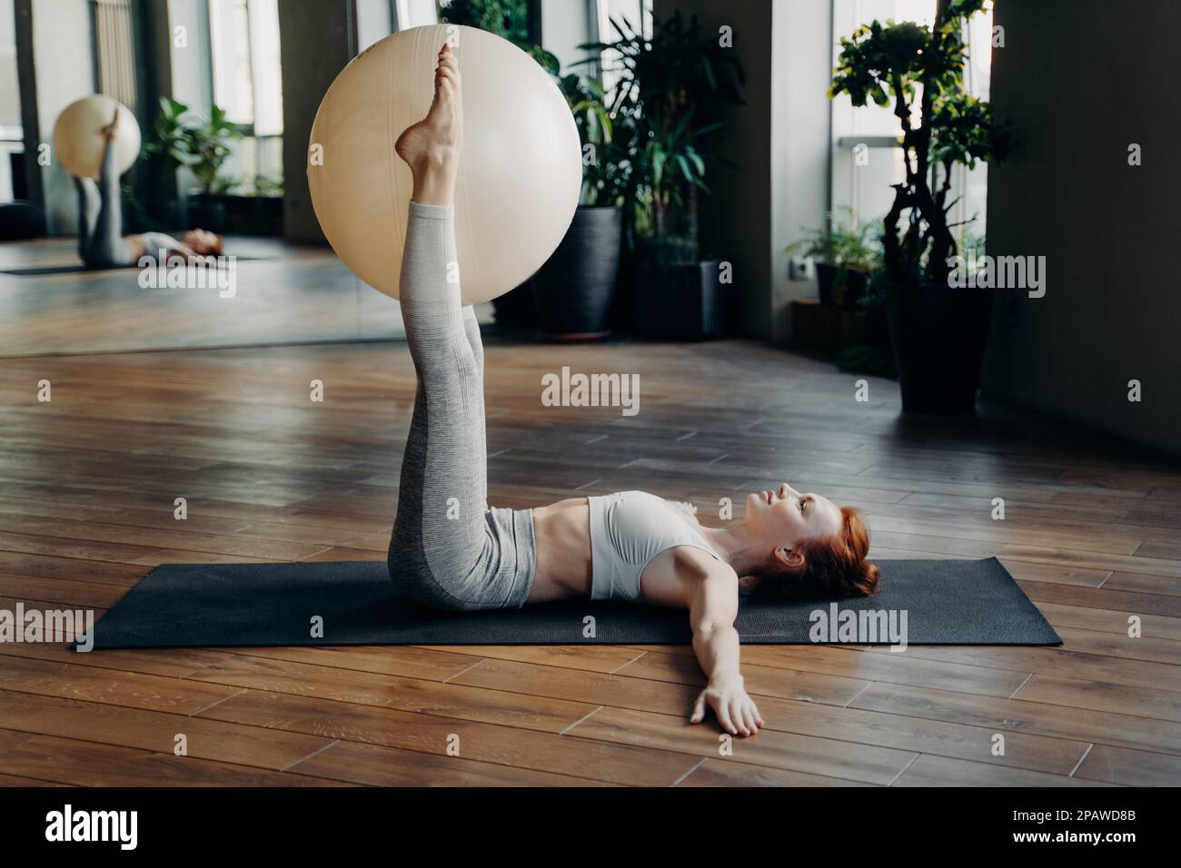 Young sportive fitness woman in grey sportswear lying on yoga mat in ...